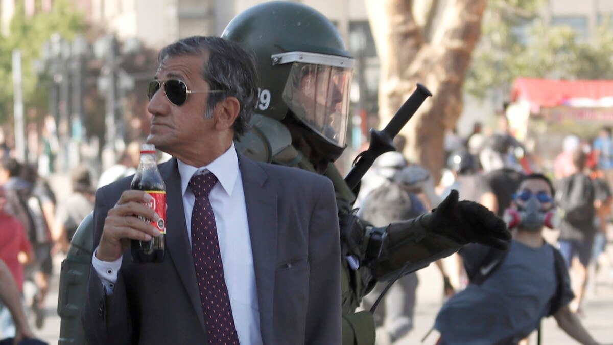 Backstory - As a Riot Rages, a Smartly-dressed Chilean Sips His Soda